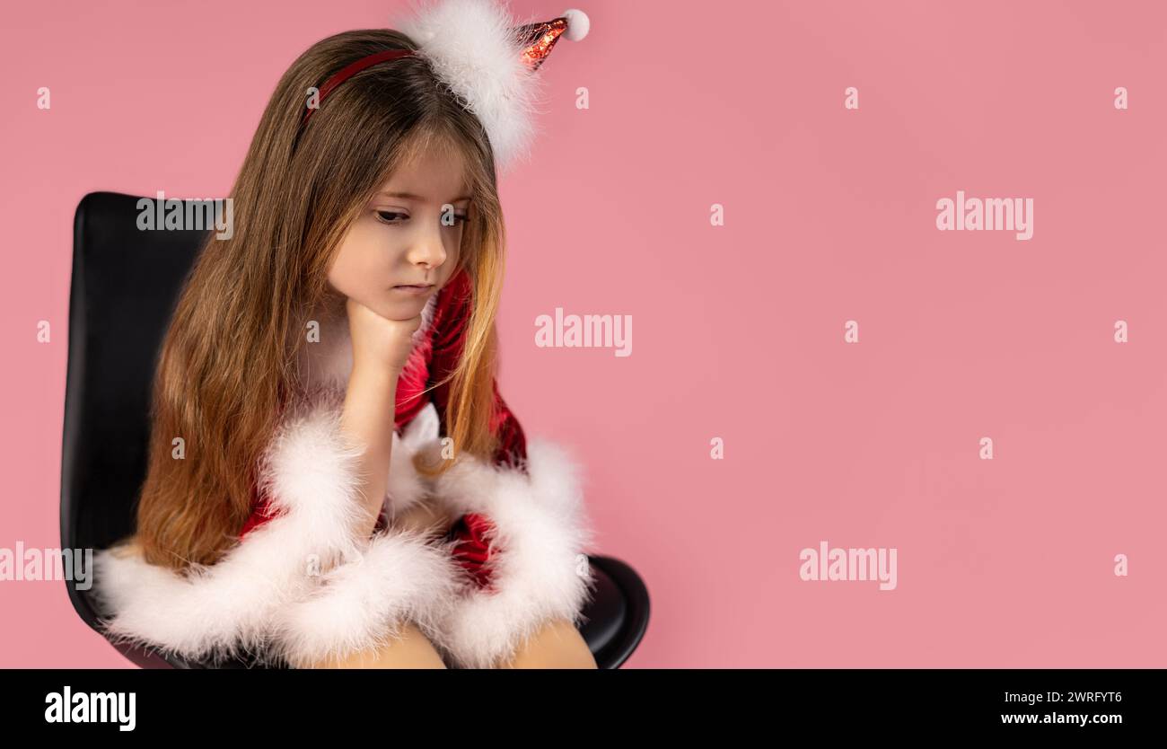 Angry little girl sits with her hand under her chin thinking when Santa ...