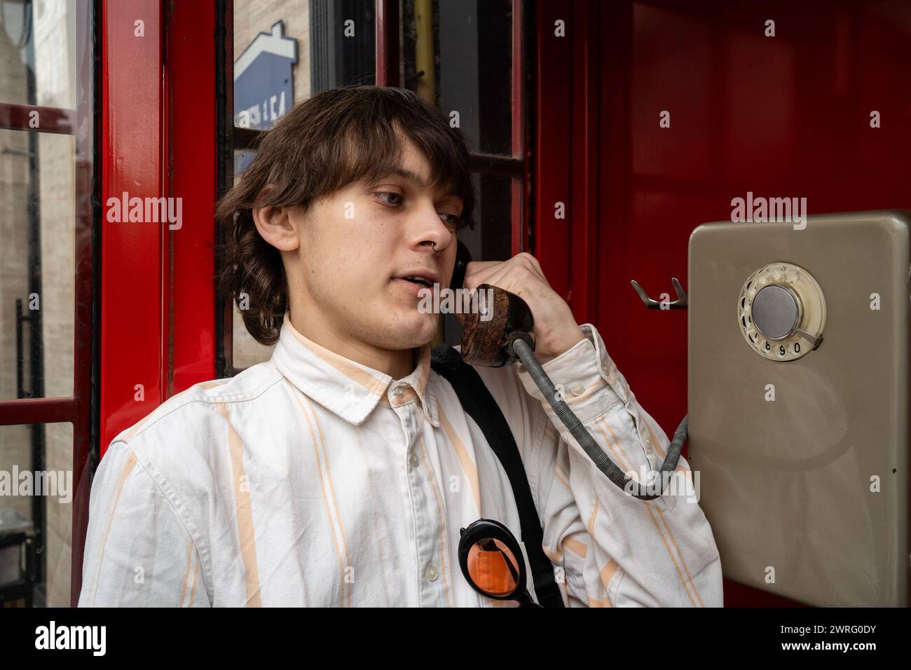Young stylish man dressed in 90s style talking in red retro old ...