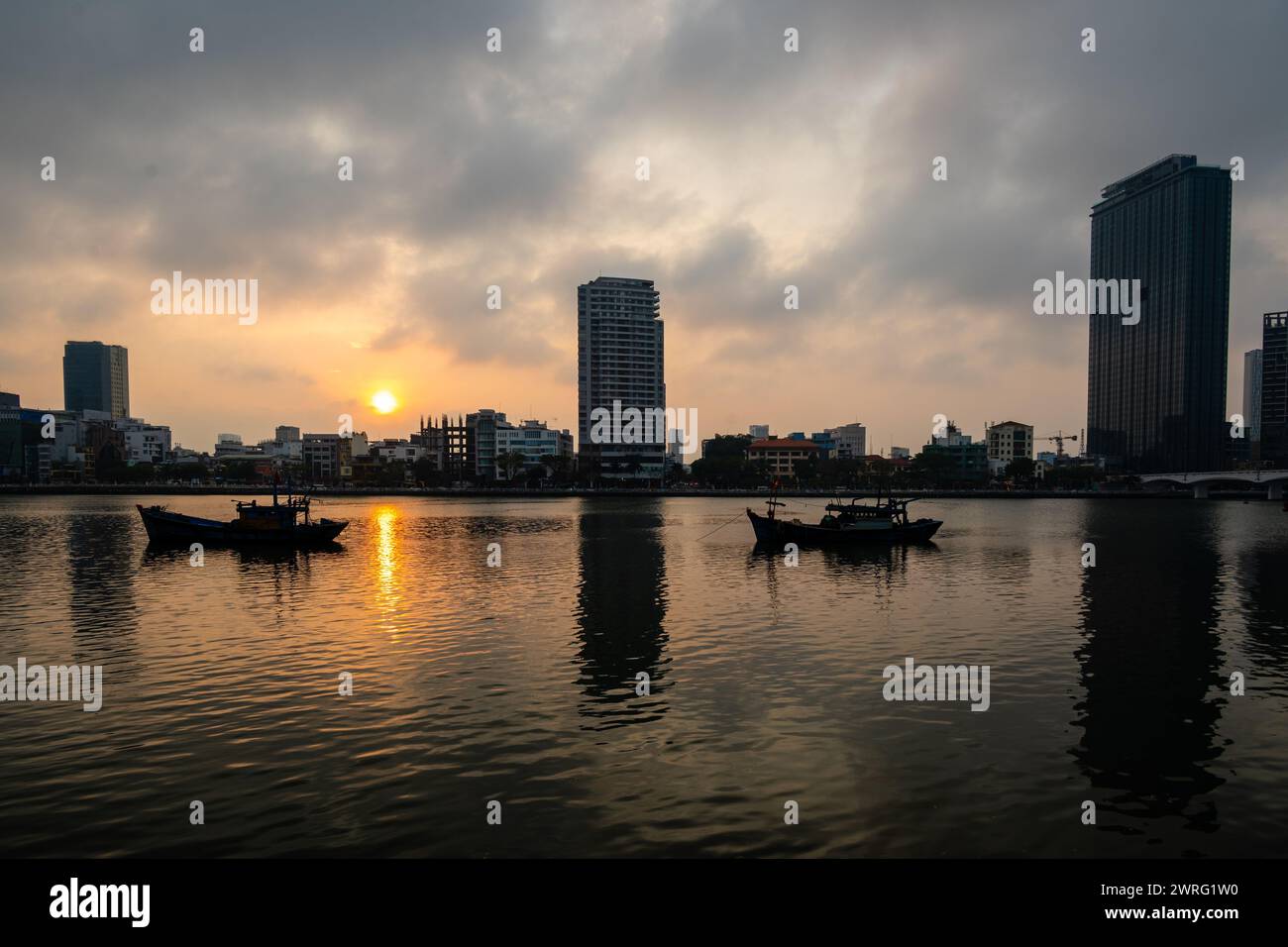 Sunset behind the skyline and fishing boats of Da Nang in Vietnam Stock ...