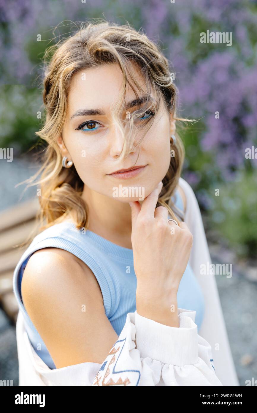 A woman with striking blue eyes is standing in a confident pose, ready ...