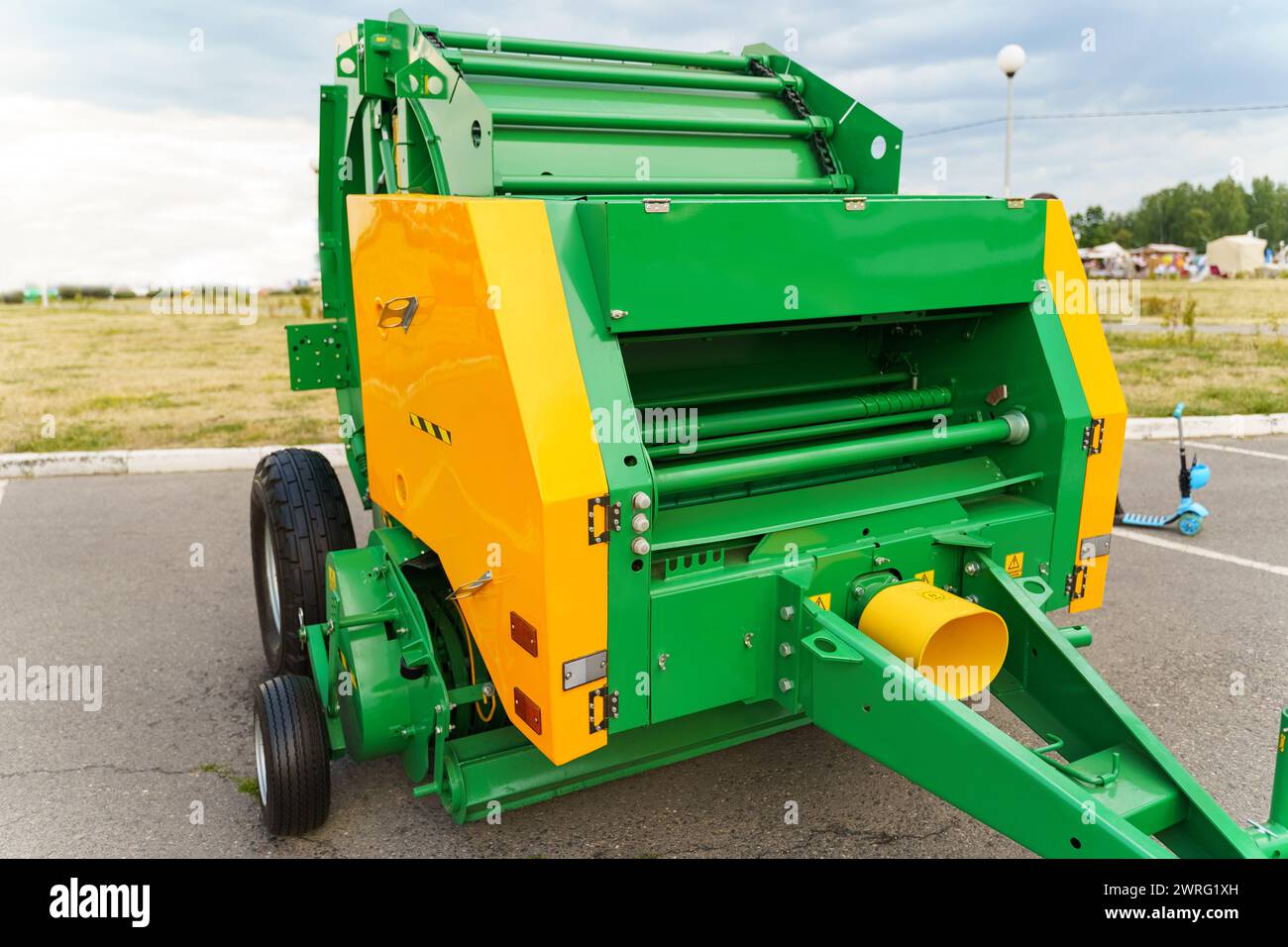 Green and yellow agricultural machine - round baler on the parking lot ...