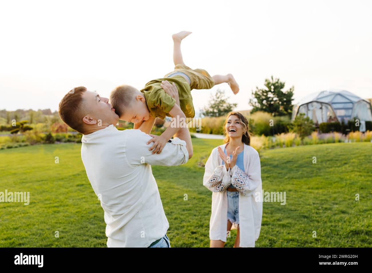 A man is lifting a young boy into the air with his arms extended ...
