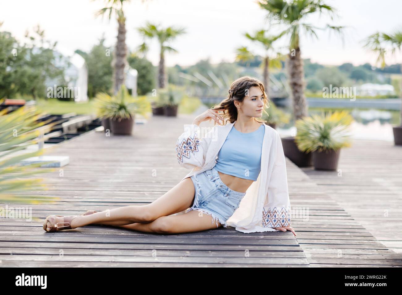 A woman is seated on a wooden floor, displaying a relaxed posture Stock ...