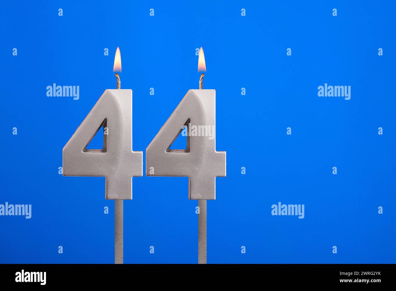 Birthday number 44 - Candle lit on blue background Stock Photo - Alamy