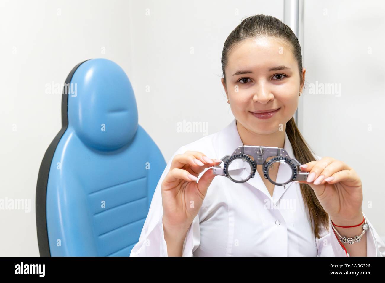 The ophthalmologist is holding a pair of glasses in her hand, with a ...