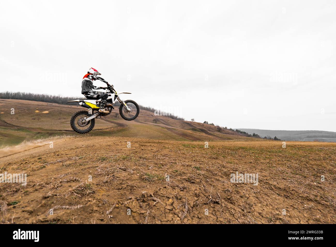 Riding a dirt bike on an offroad path, wearing a helmet for safety. The ...
