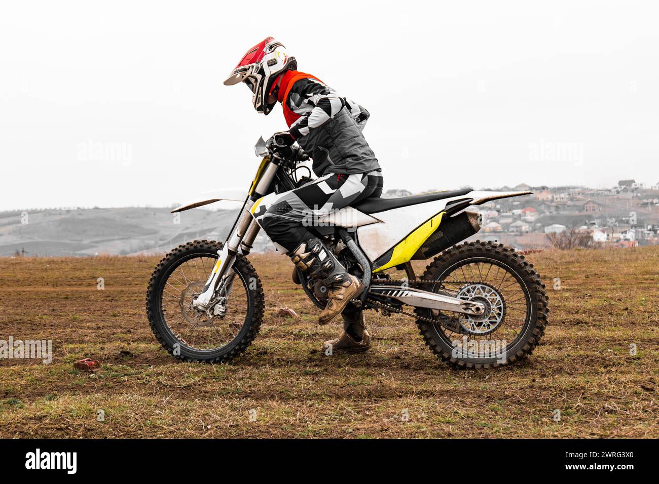 A motorcycle racer with a helmet is riding a dirt bike equipped with ...
