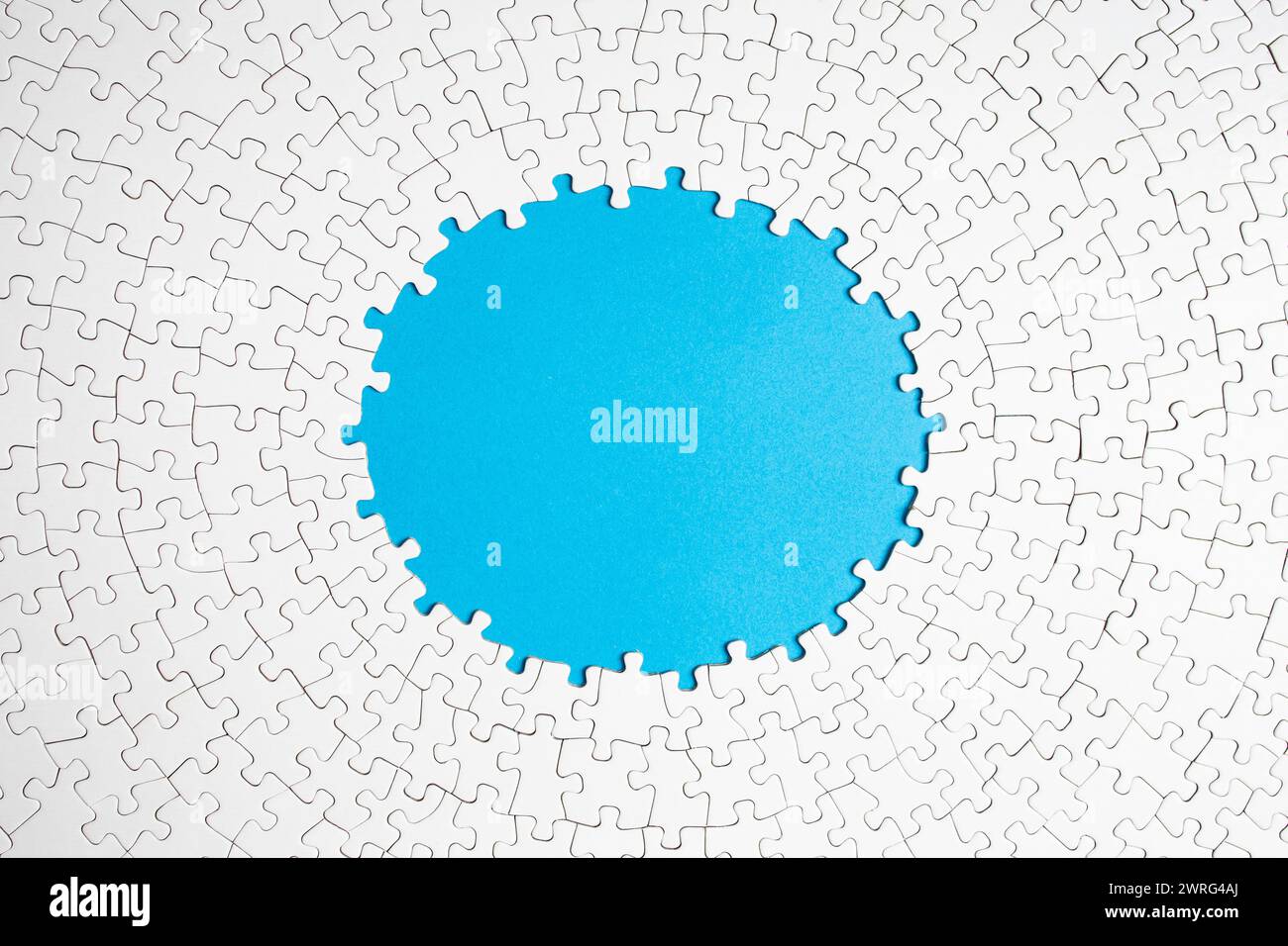 Plain white jigsaw puzzle on blue color background, oval shaped frame ...