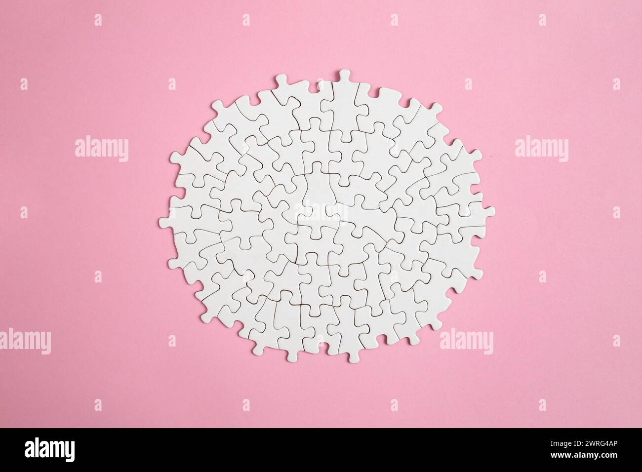 Plain white jigsaw puzzle on pink color background, oval shaped frame ...