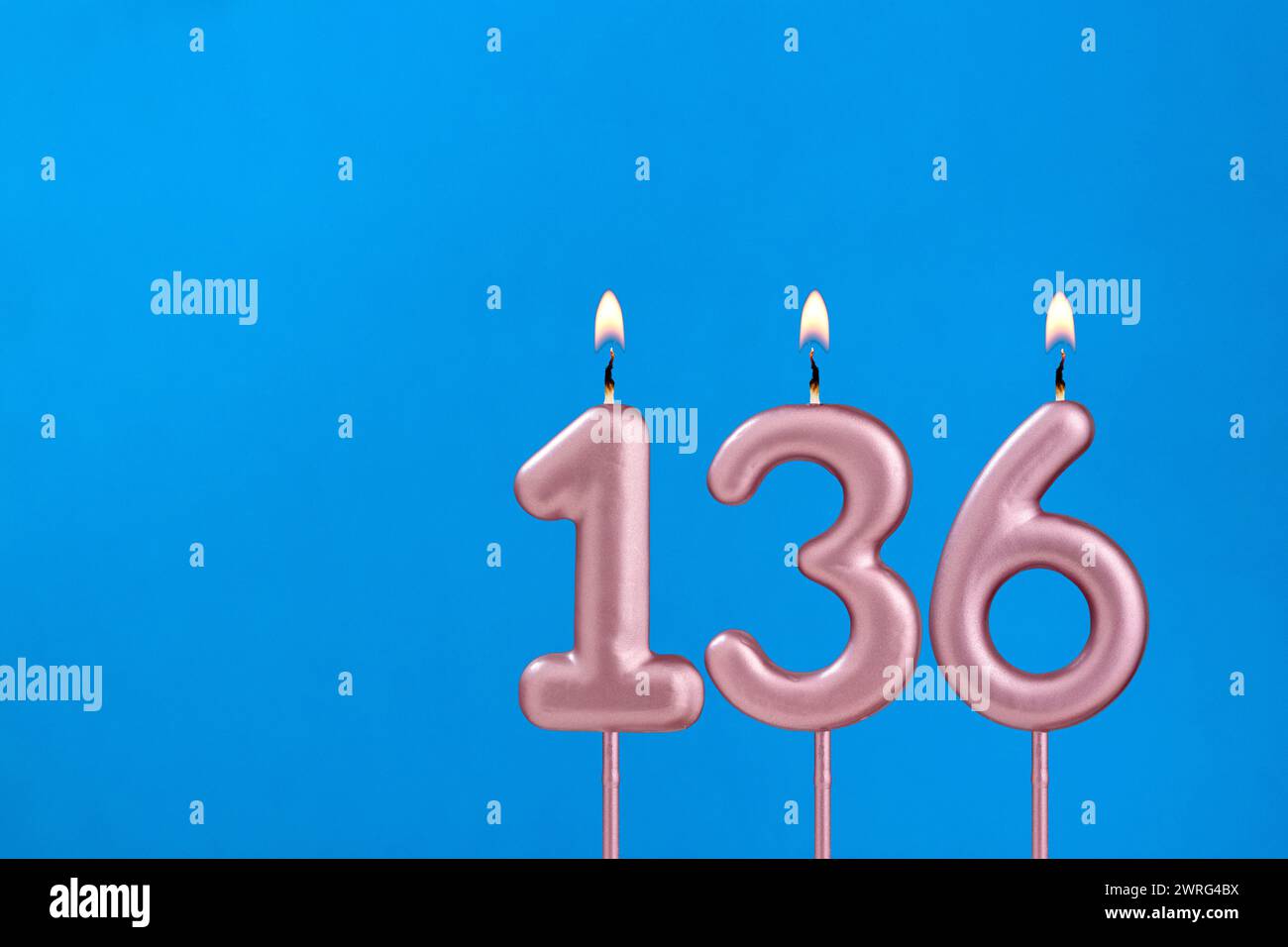Number 136 - Burning anniversary candle on blue foamy background Stock ...