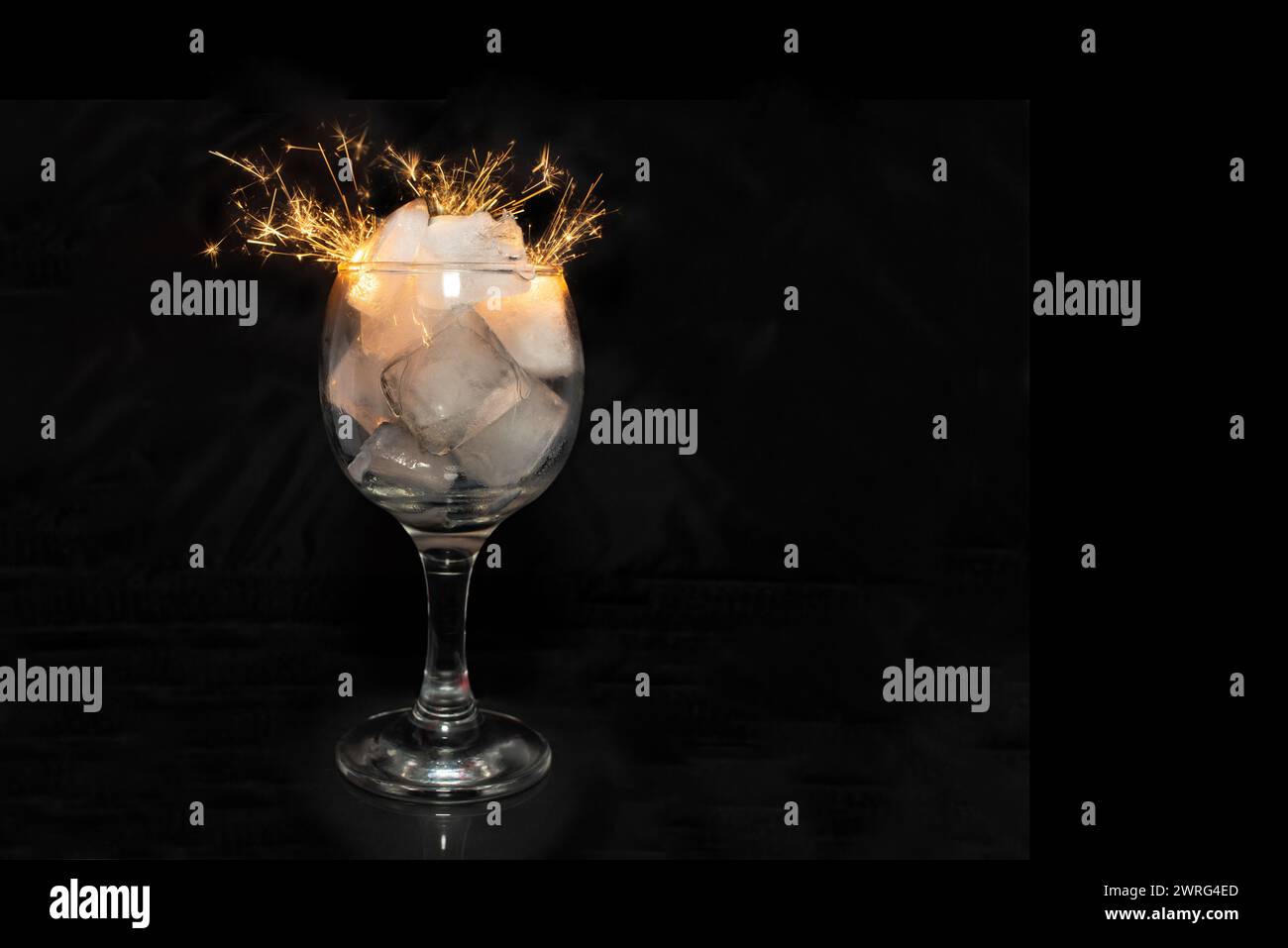 Wine glass filled with ice cubes and sparkler fireworks isolated on ...