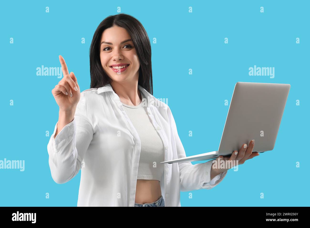 Female programmer working with laptop pointing at something on blue ...