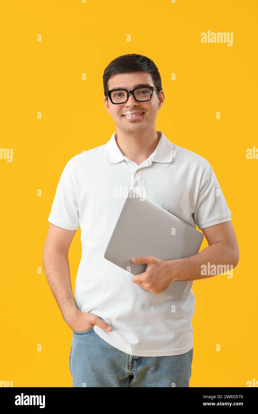 Male programmer with laptop on yellow background Stock Photo - Alamy