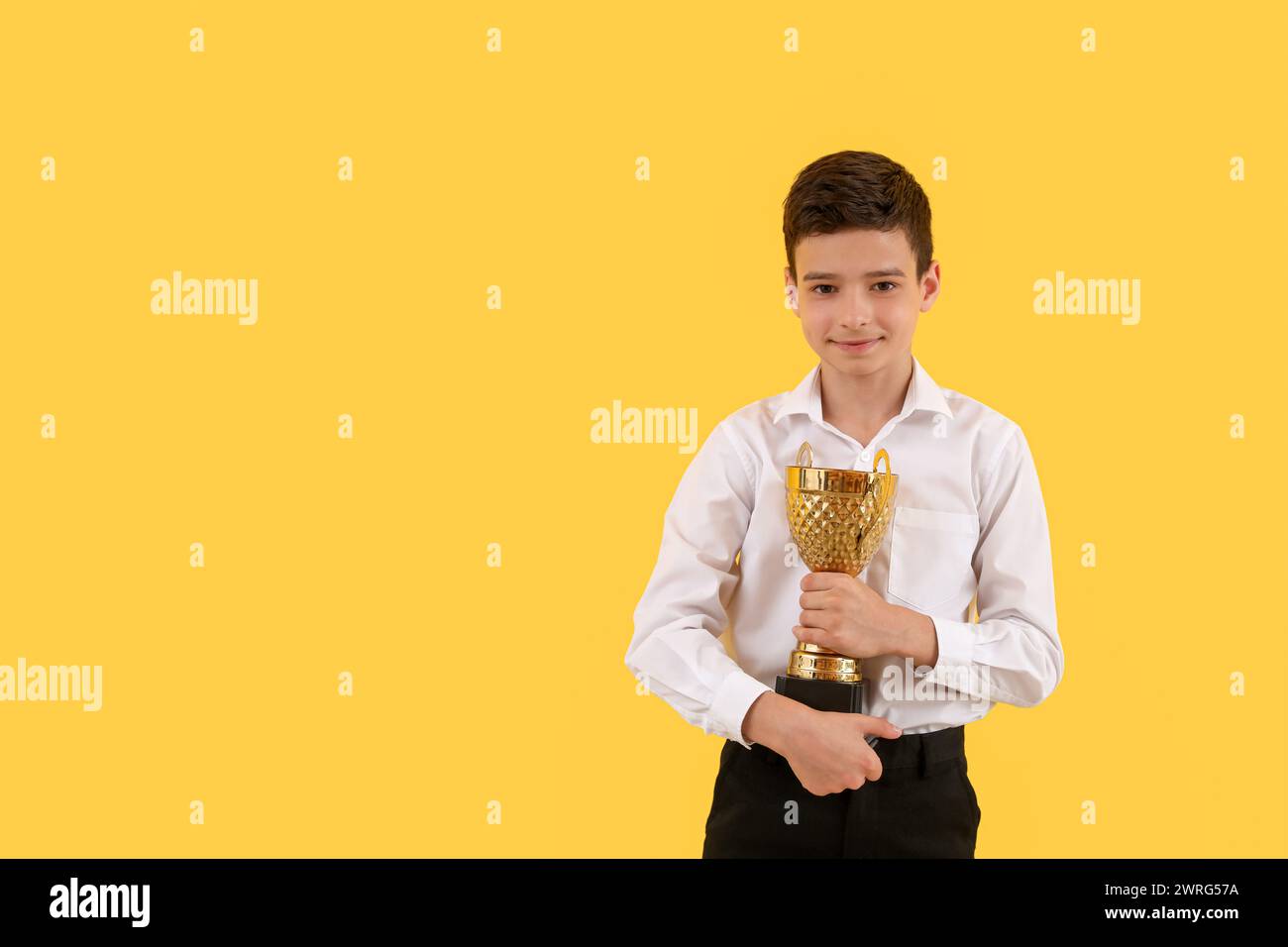 Smart little school boy with prize cup on yellow background Stock Photo ...