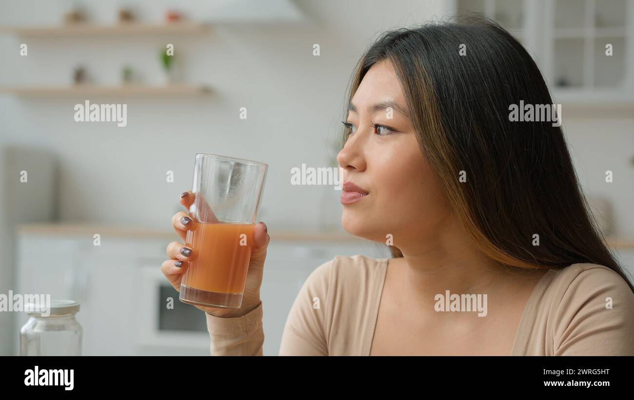 Korean woman drinking fresh smoothie orange juice. Asian vegetarian ...