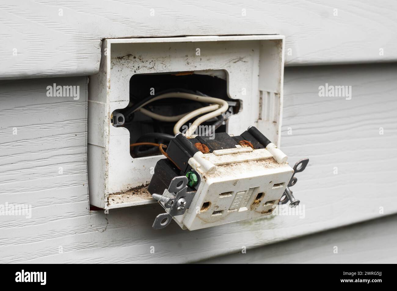 Weathered exterior electrical outlet hanging from attached wiring Stock ...