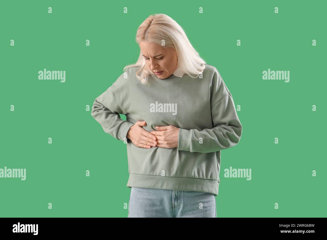 Mature woman suffering from side pain on green background Stock Photo ...