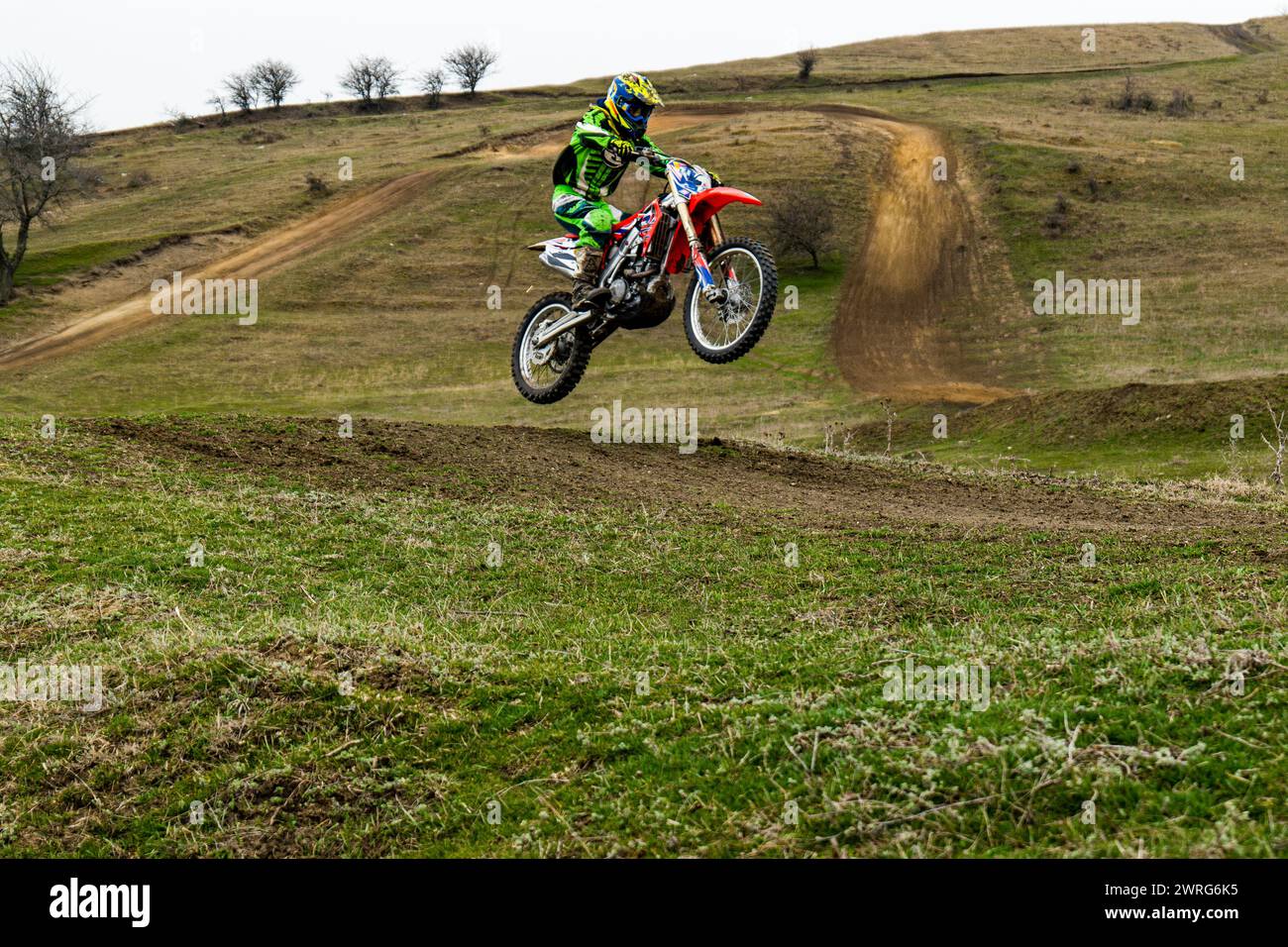 A motorcycle racer on a dirt bike is soaring through the air, wearing a ...