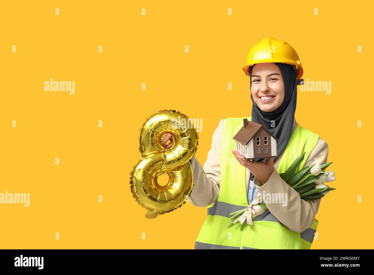 Muslim female construction worker with toy house, white tulips and ...