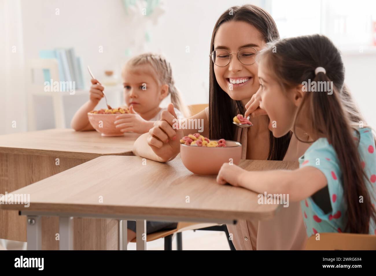 Little girl with nursery teacher having breakfast in kindergarten Stock ...