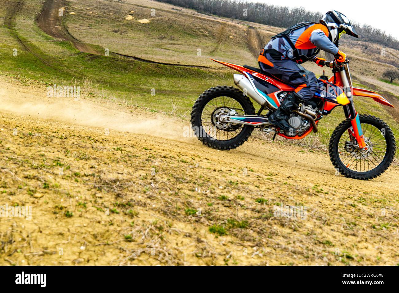 A man is riding a motorcycle on a motocross dirt track, wearing a ...
