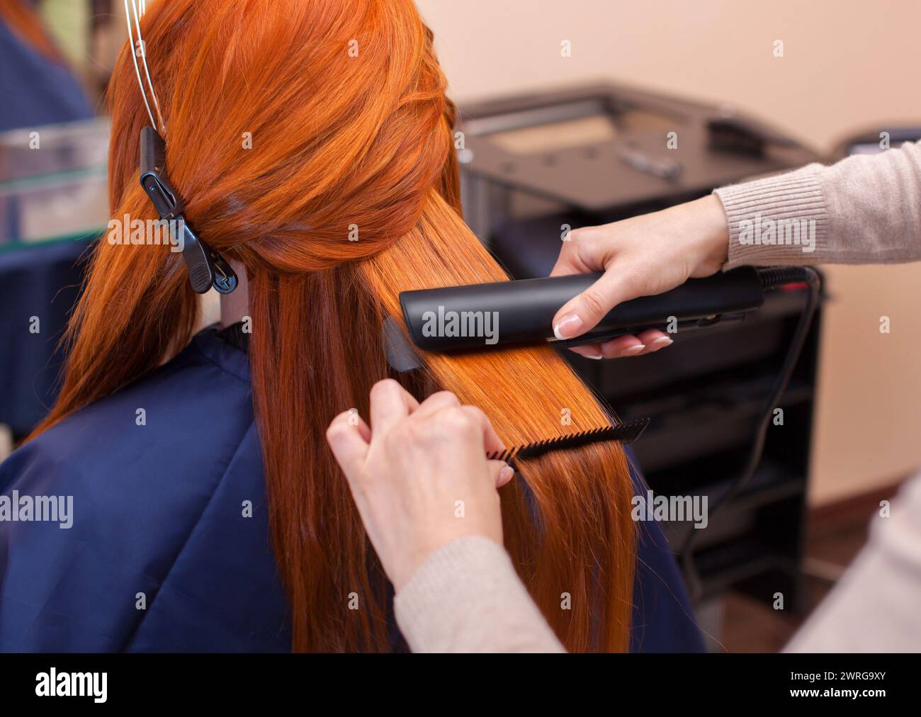 Hairdresser makes hairstyle girl with long red hair in a beauty salon ...