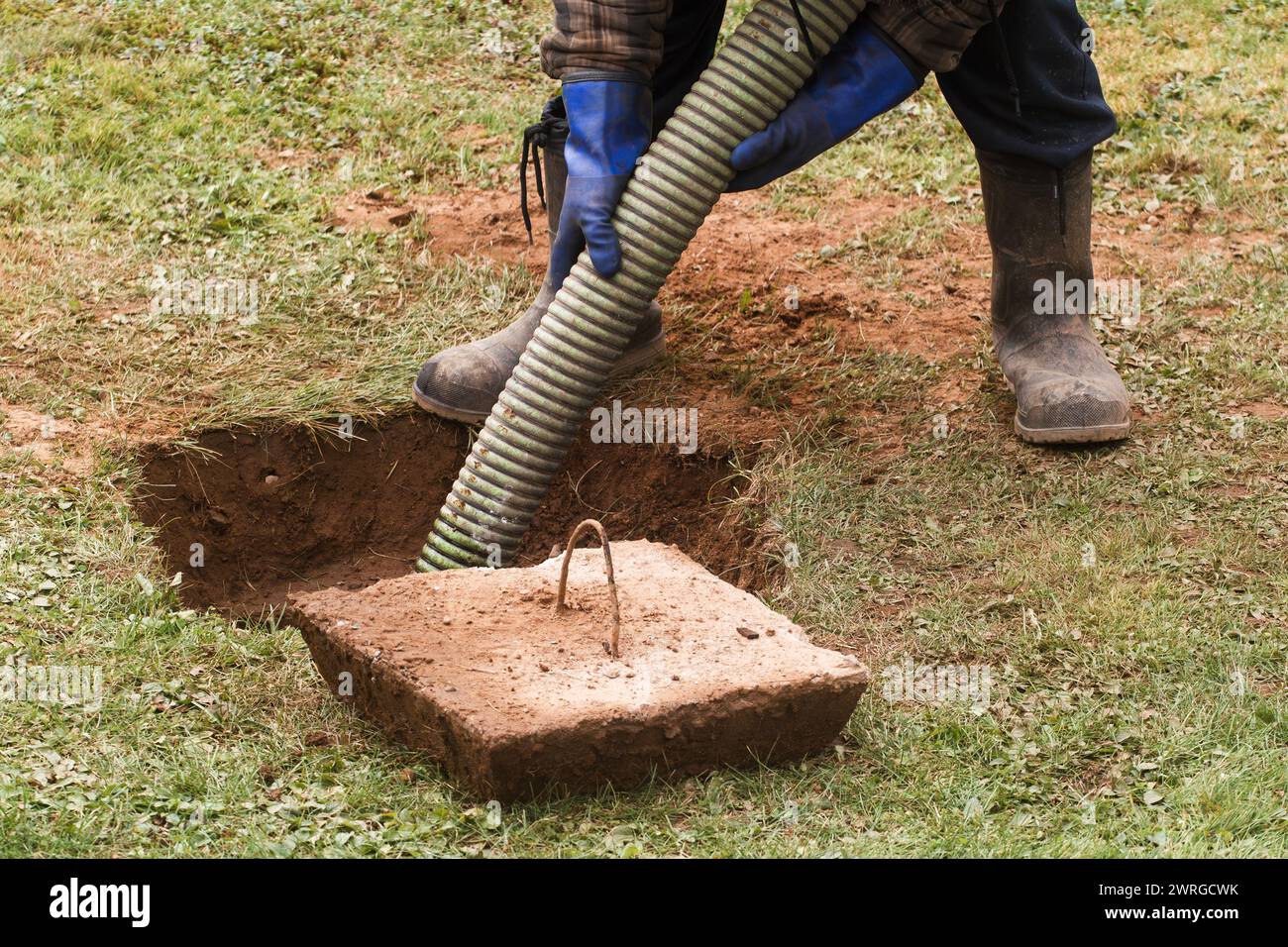 Waste management worker pumping out a residential septic tank Stock ...