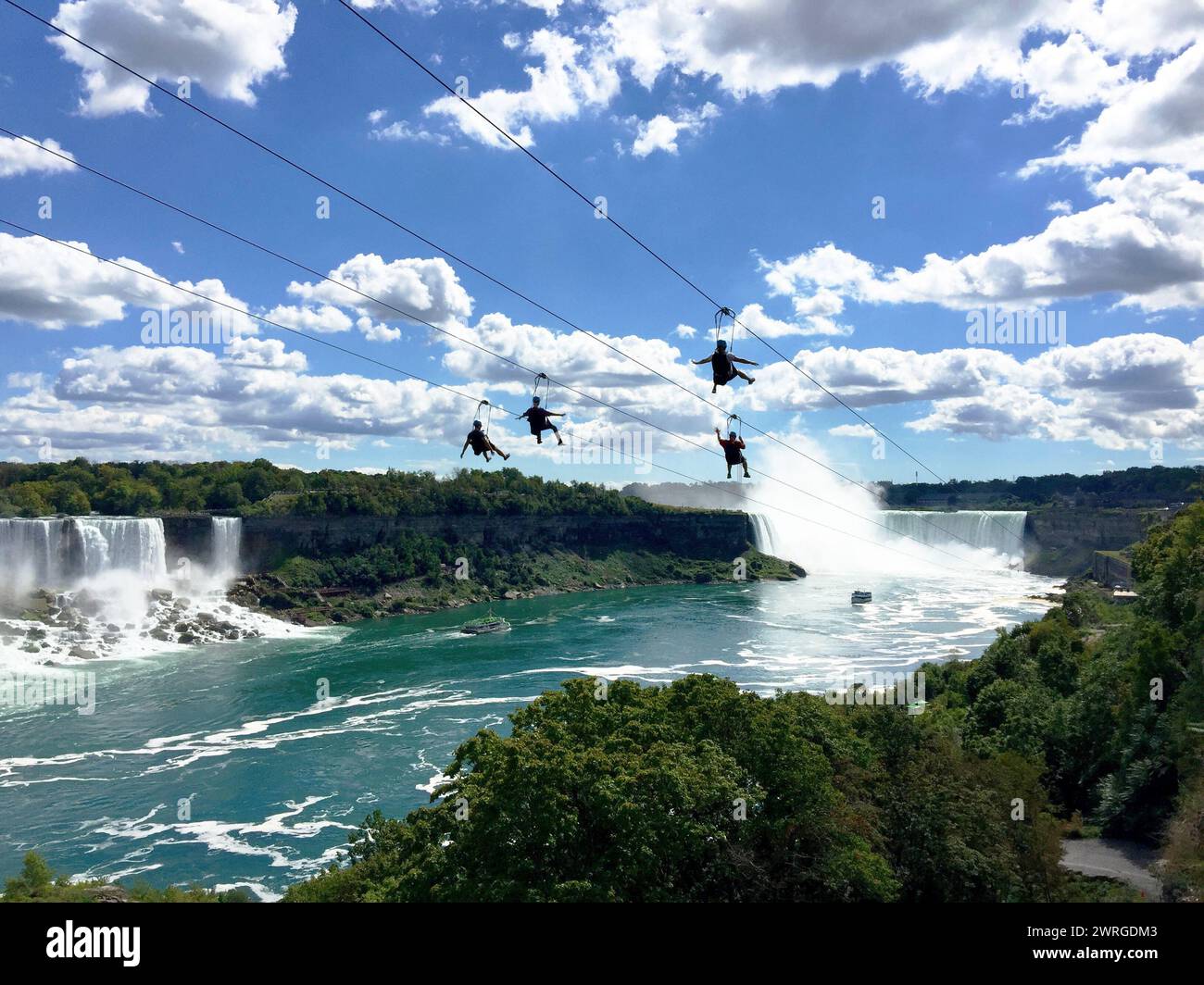 Riders gliding on the zipline to the falls at Niagara Falls, Ontario ...