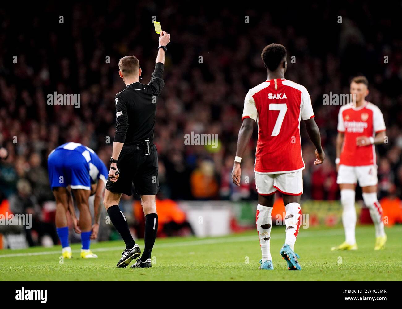 Referee Clement Turpin shows a yellow card to Arsenal's William Saliba ...