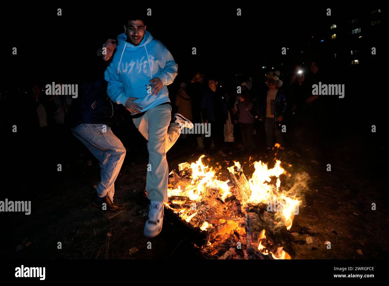 A man jumps over a bonfire as people celebrate Chaharshanbe Souri, or ...