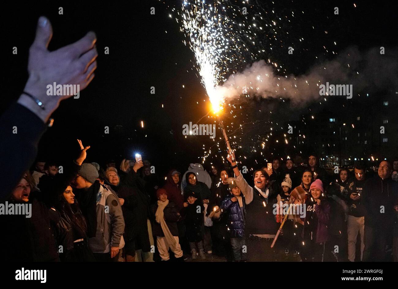 A woman holds up a firework as people celebrate Chaharshanbe Souri, or ...