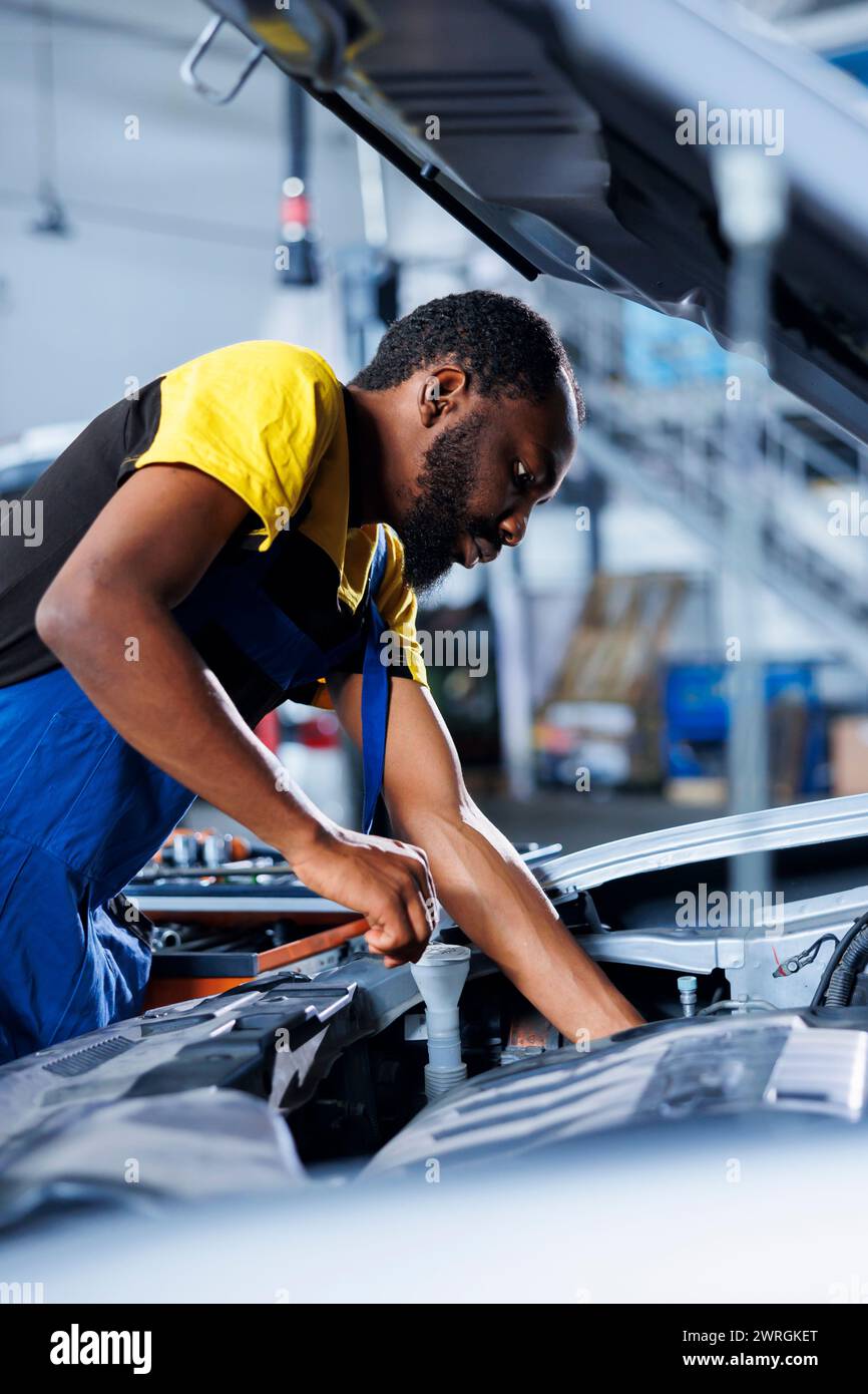 Engineer expertly examines car battery using advanced mechanical tools ...