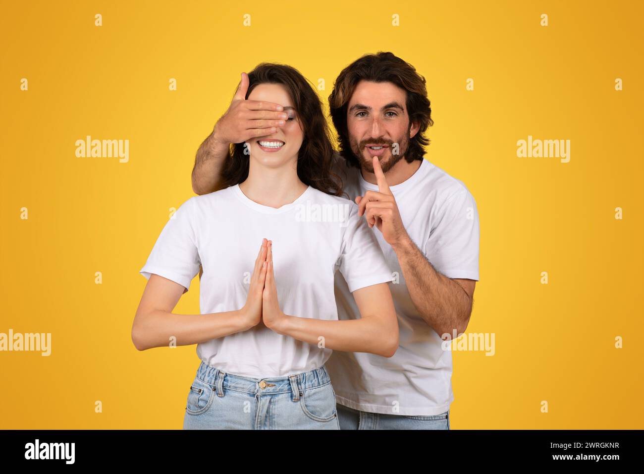 Playful man with a beard covering a woman's eyes with his hand, making ...