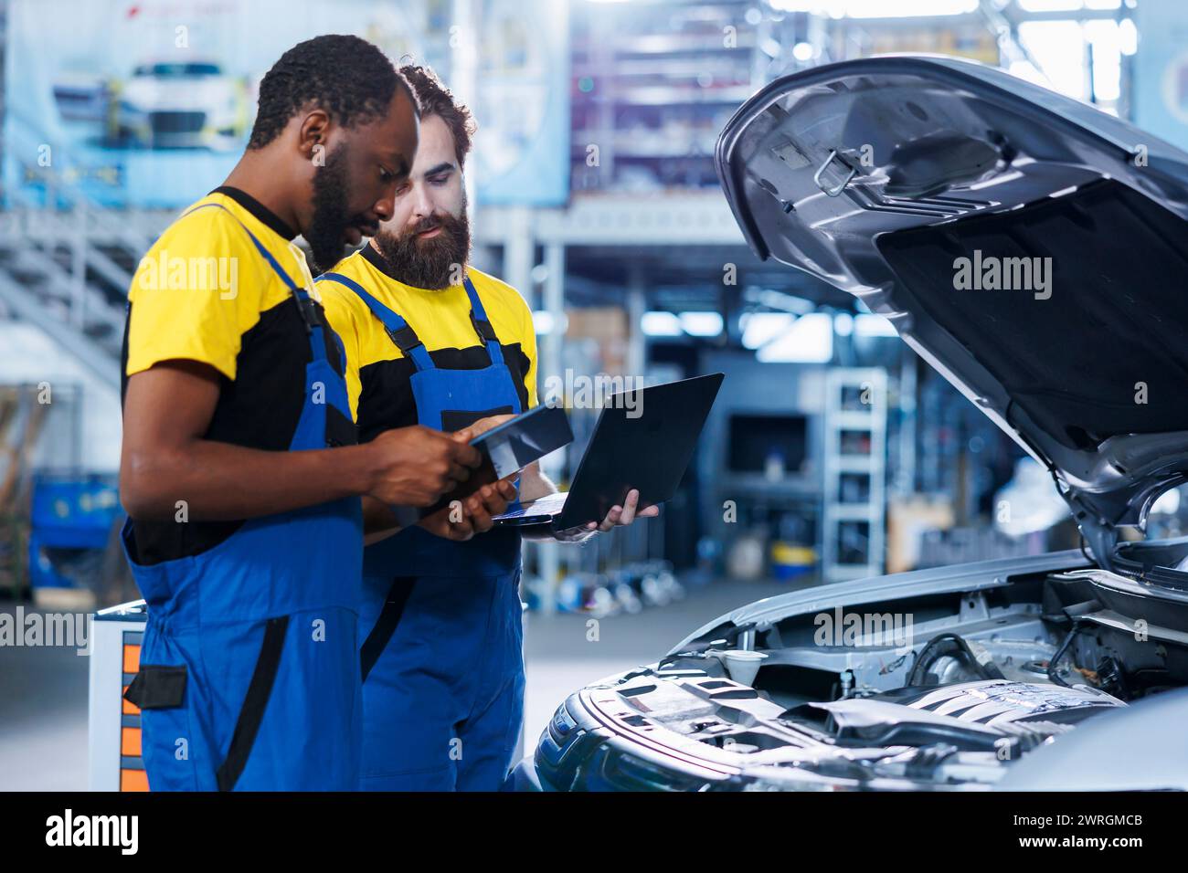 Coworkers in car service using tablet to calculate repairments invoice ...
