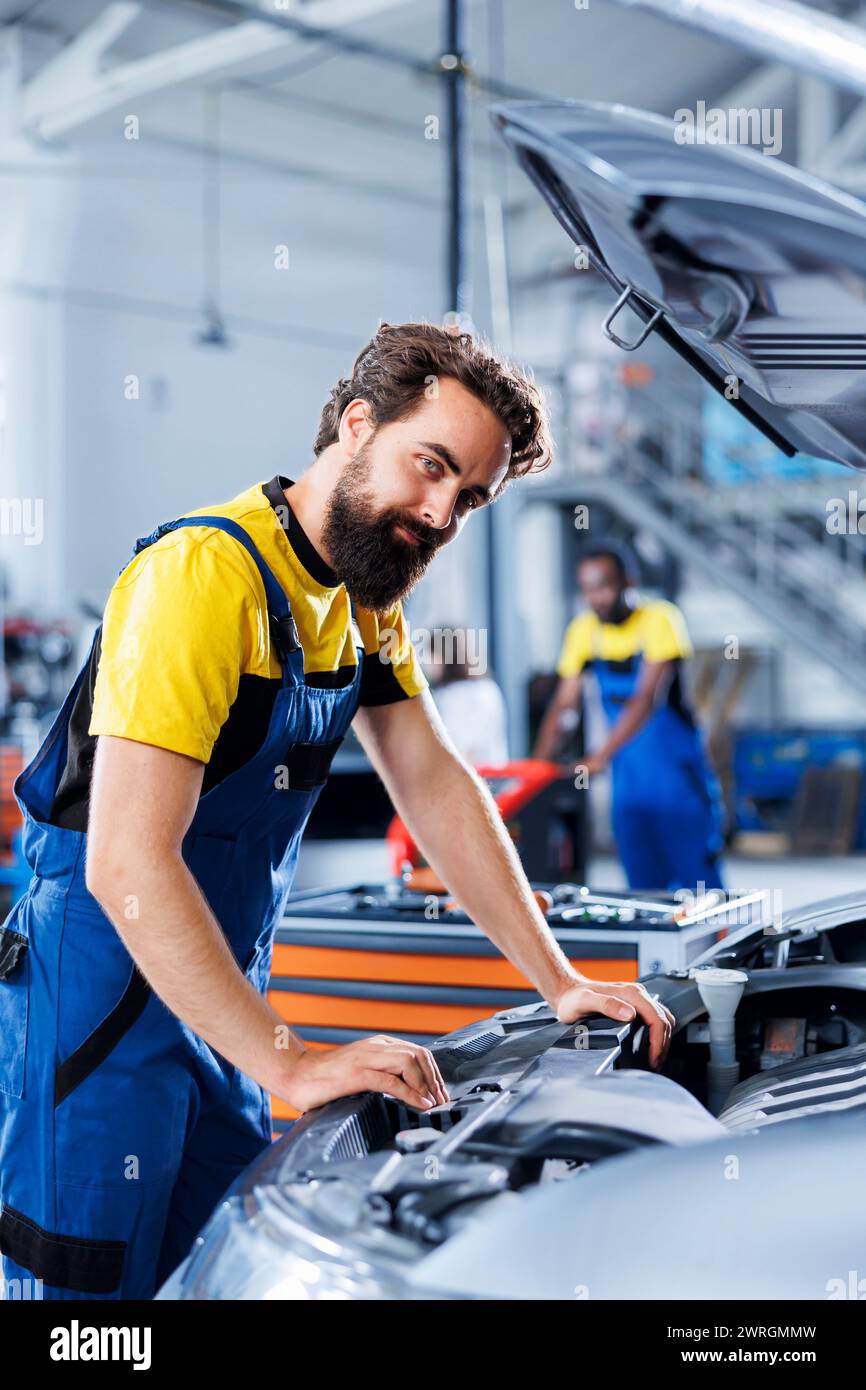 Portrait of car service mechanic examining broken engine using advanced ...