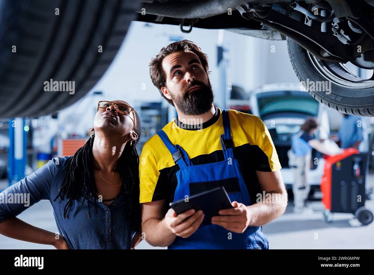 Hardworking specialist helping customer with car checkup in auto repair ...