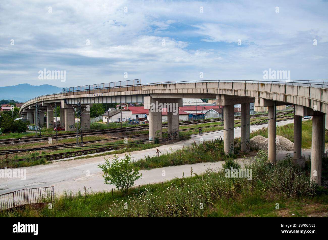 An overpass (bridge) built of concrete pillars and asphalt passes over ...
