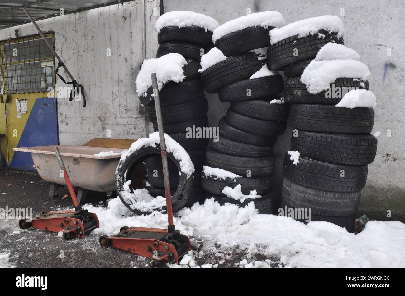 A pile of old used tires and several jacks lined up in front of a ...