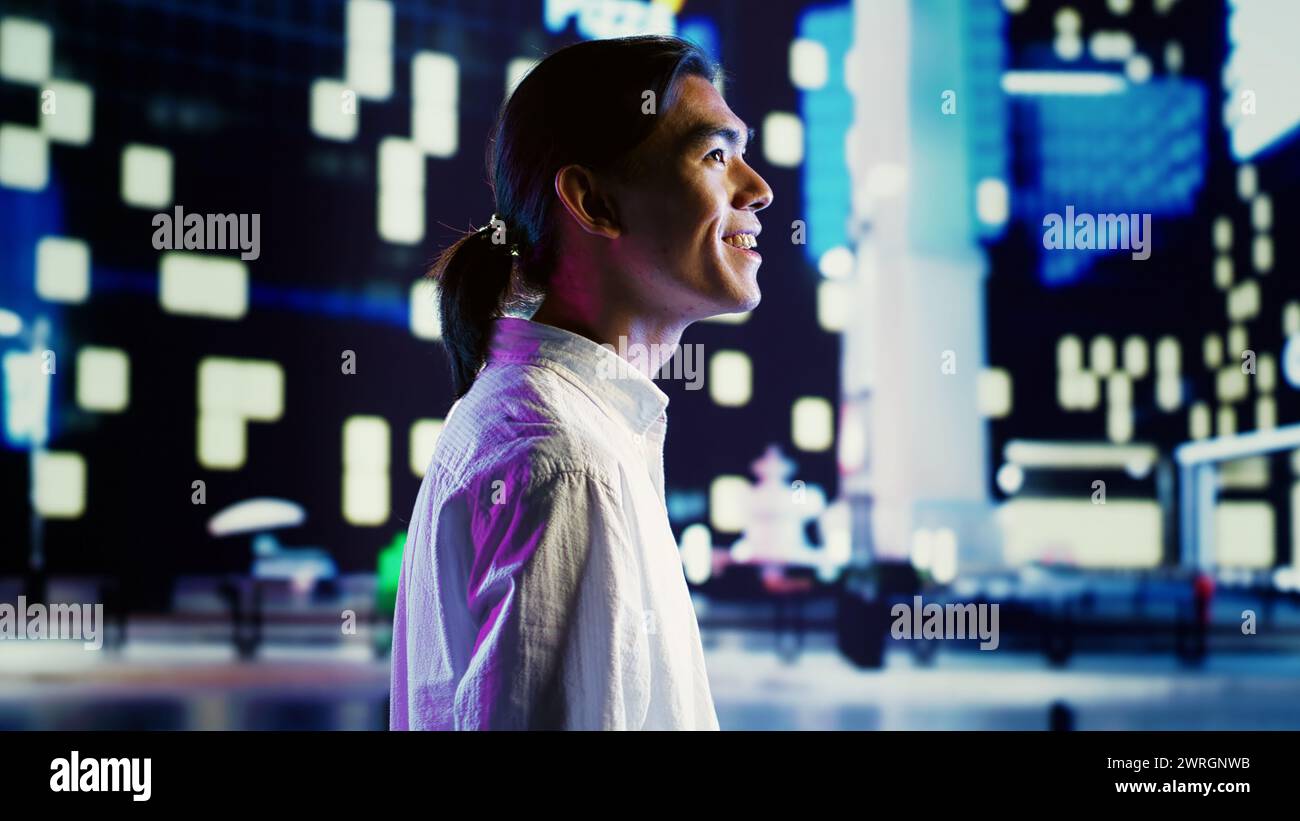 Asian man wandering around city streets at night, looking upwards to ...