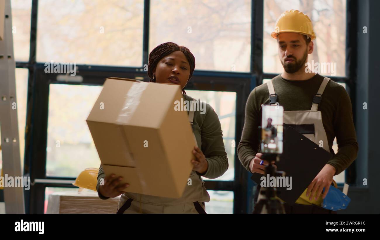 Warehouse employees using smartphone placed on tripod to make video for ...