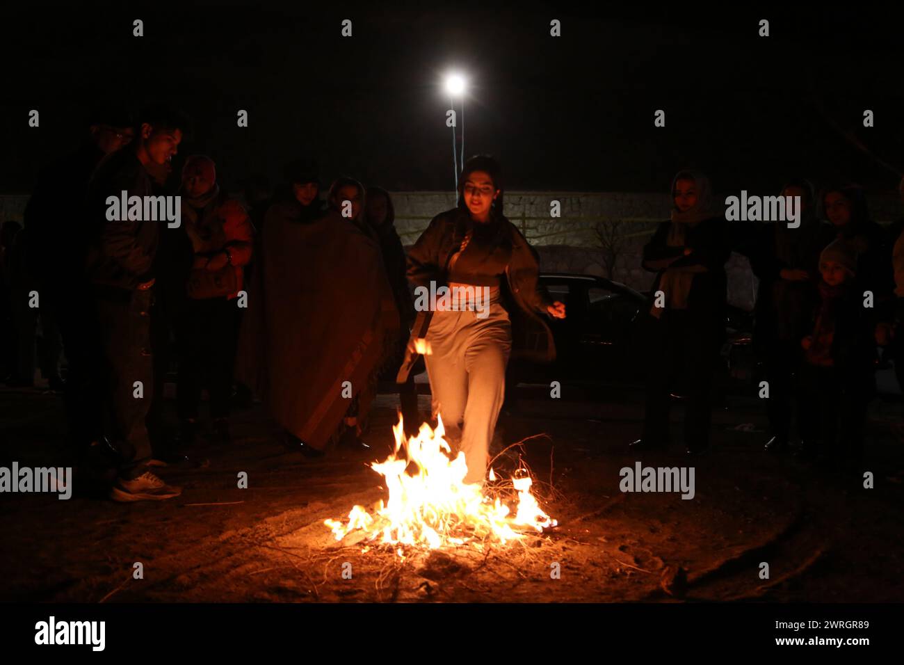 March 12, 2024, Tehran, Iran: An Iranian woman jumps over a bonfire on ...