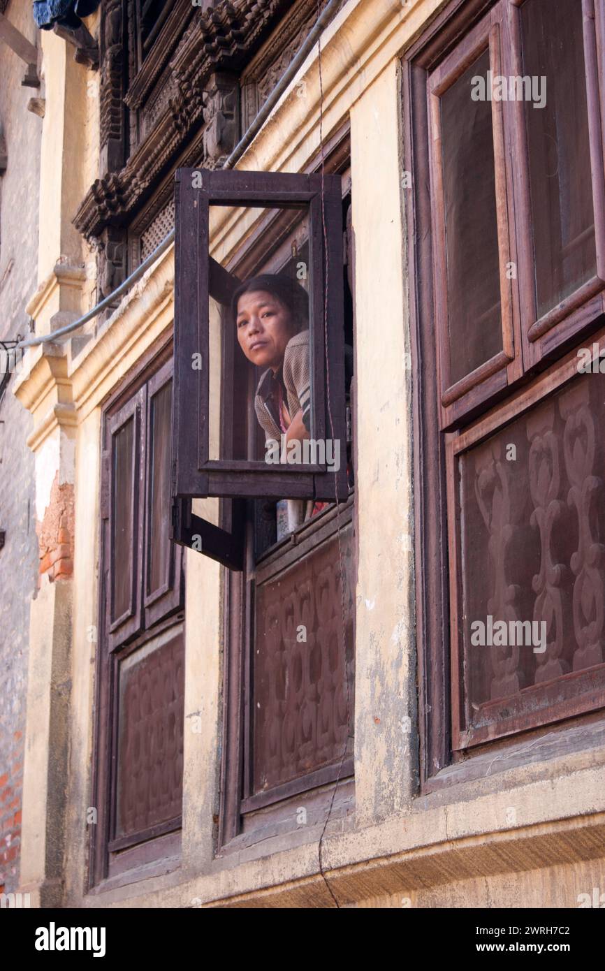 KATHMANDU, NEPAL - NOVEMBER 06, 2006: The woman watch from a home's ...