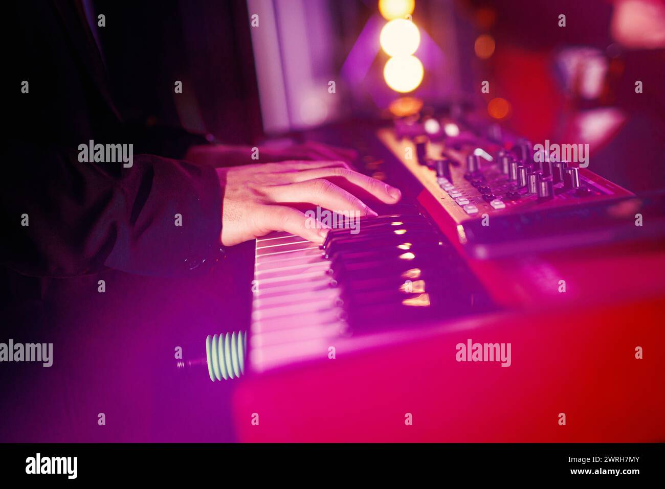 A musician plays modern piano keyboards during a concert performance ...