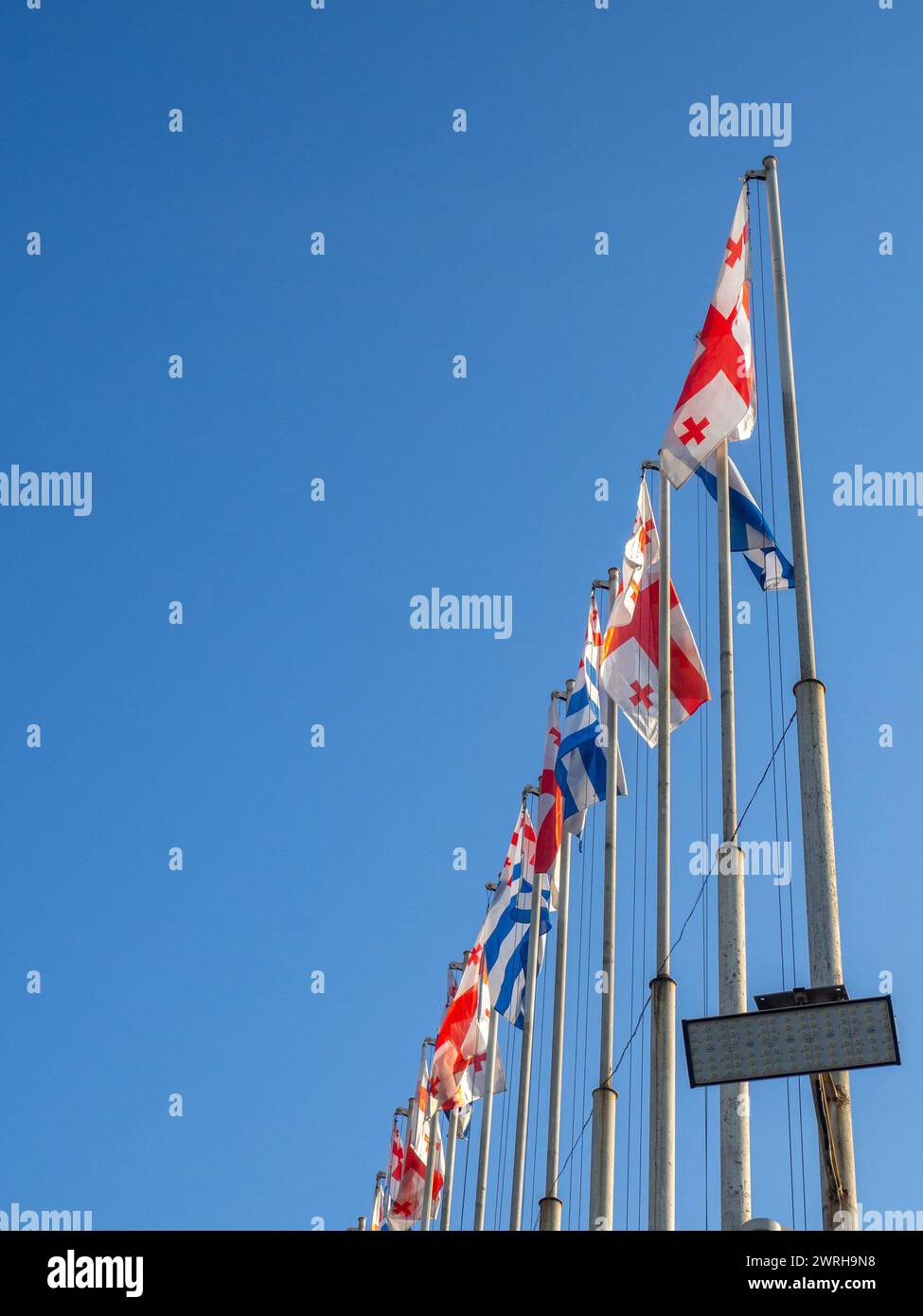 Flags of Georgia and Adjara on flagpoles. Many flags against the sky ...