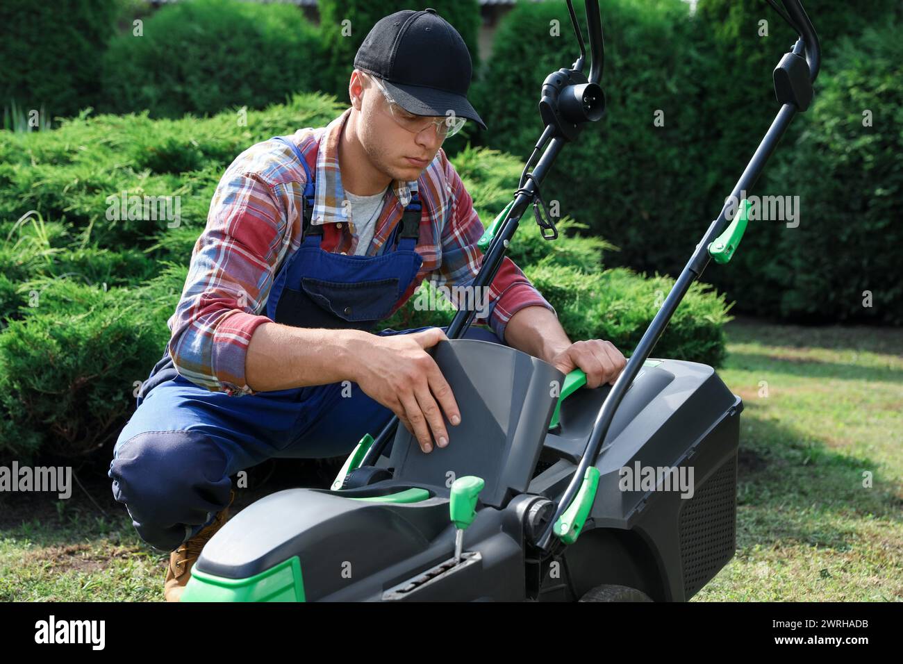 Cleaning lawn mower. Young man detaching grass catcher from device in ...
