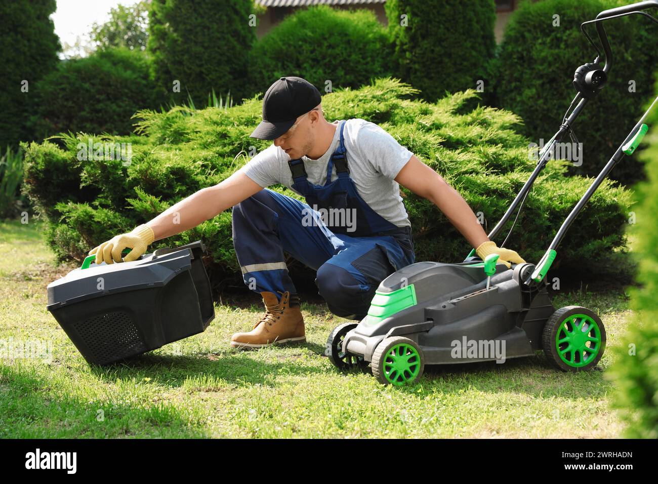 Cleaning lawn mower. Young man detaching grass catcher from device in ...