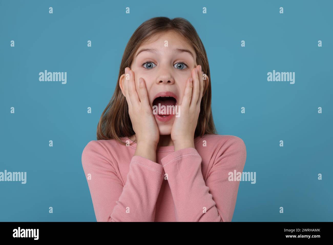 Portrait of surprised girl on light blue background Stock Photo - Alamy