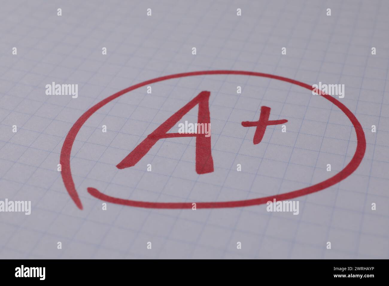School grade. Red letter A with plus symbol on notebook paper, closeup ...