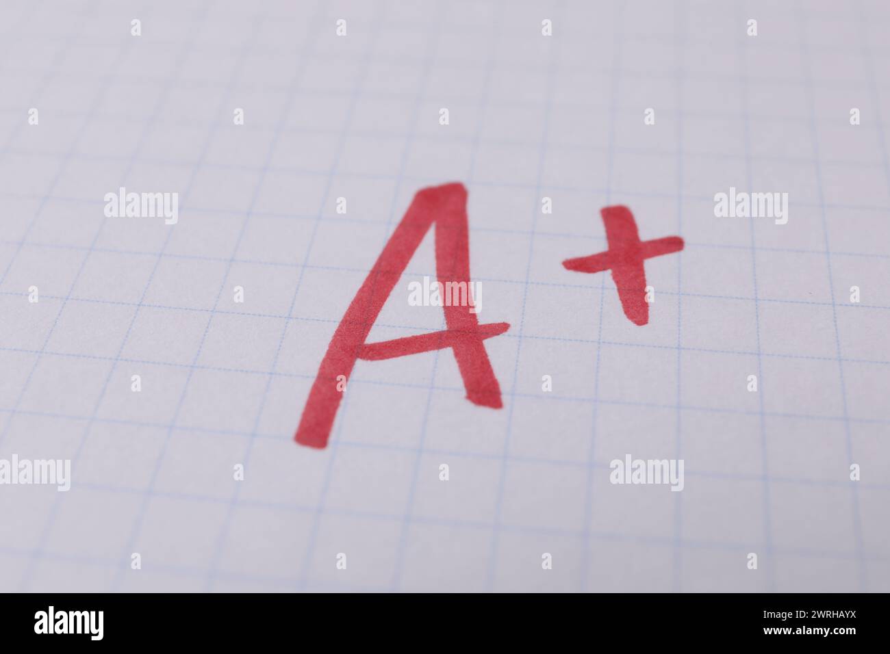 School grade. Red letter A with plus symbol on notebook paper, closeup ...