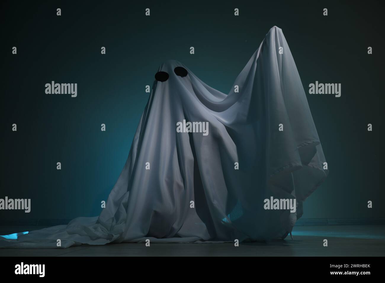 Creepy ghost. Woman covered with sheet on dark teal background Stock ...